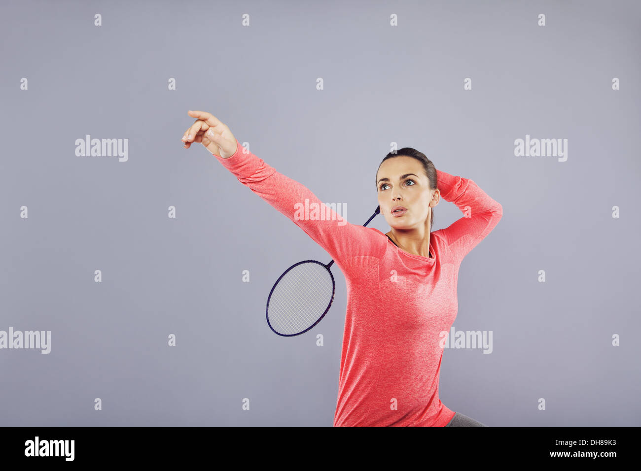 Beautiful young female playing badminton on grey background. Attractive ...