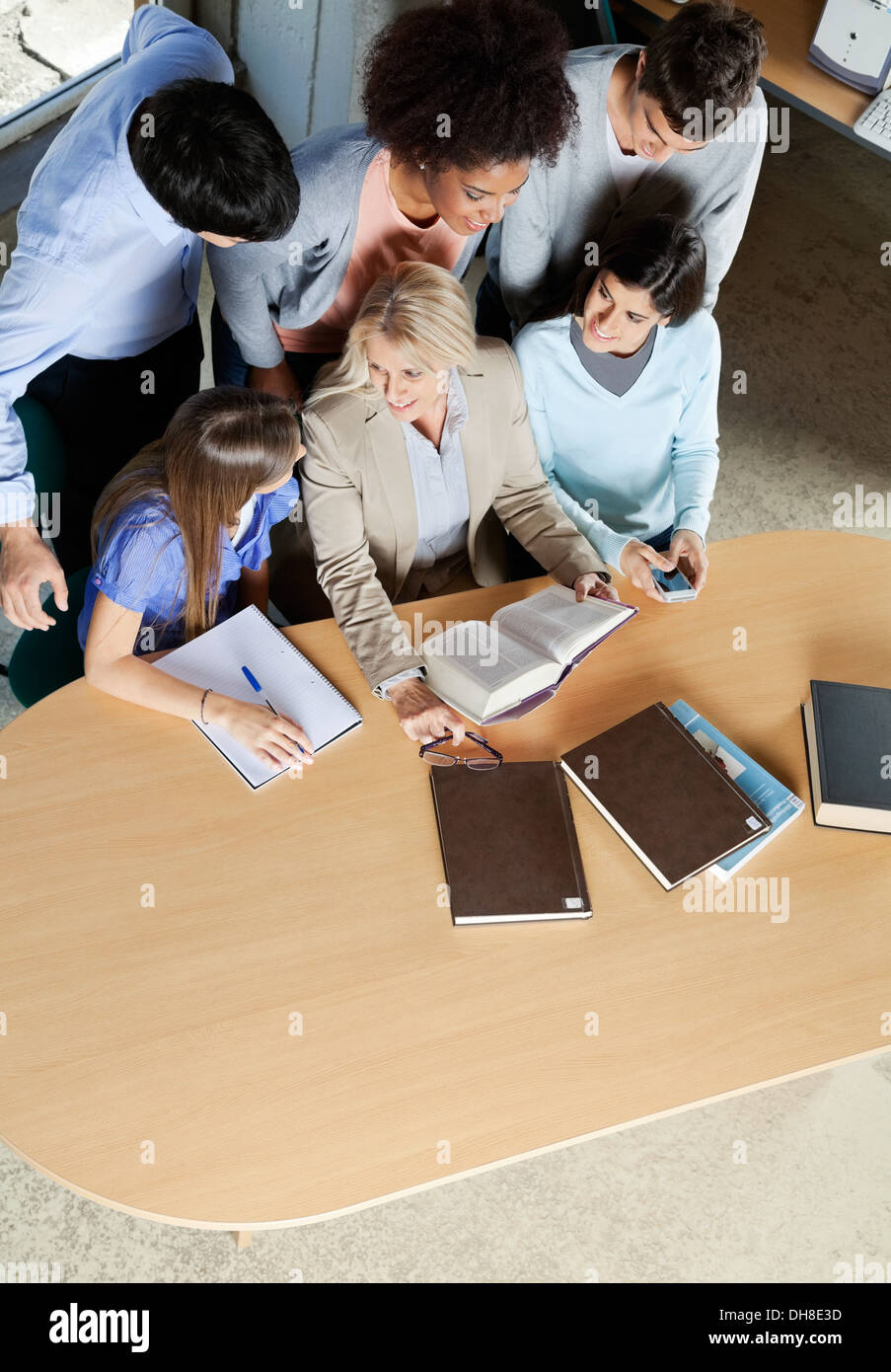 Teacher Discussing With Students At Desk In Classroom Stock Photo - Alamy