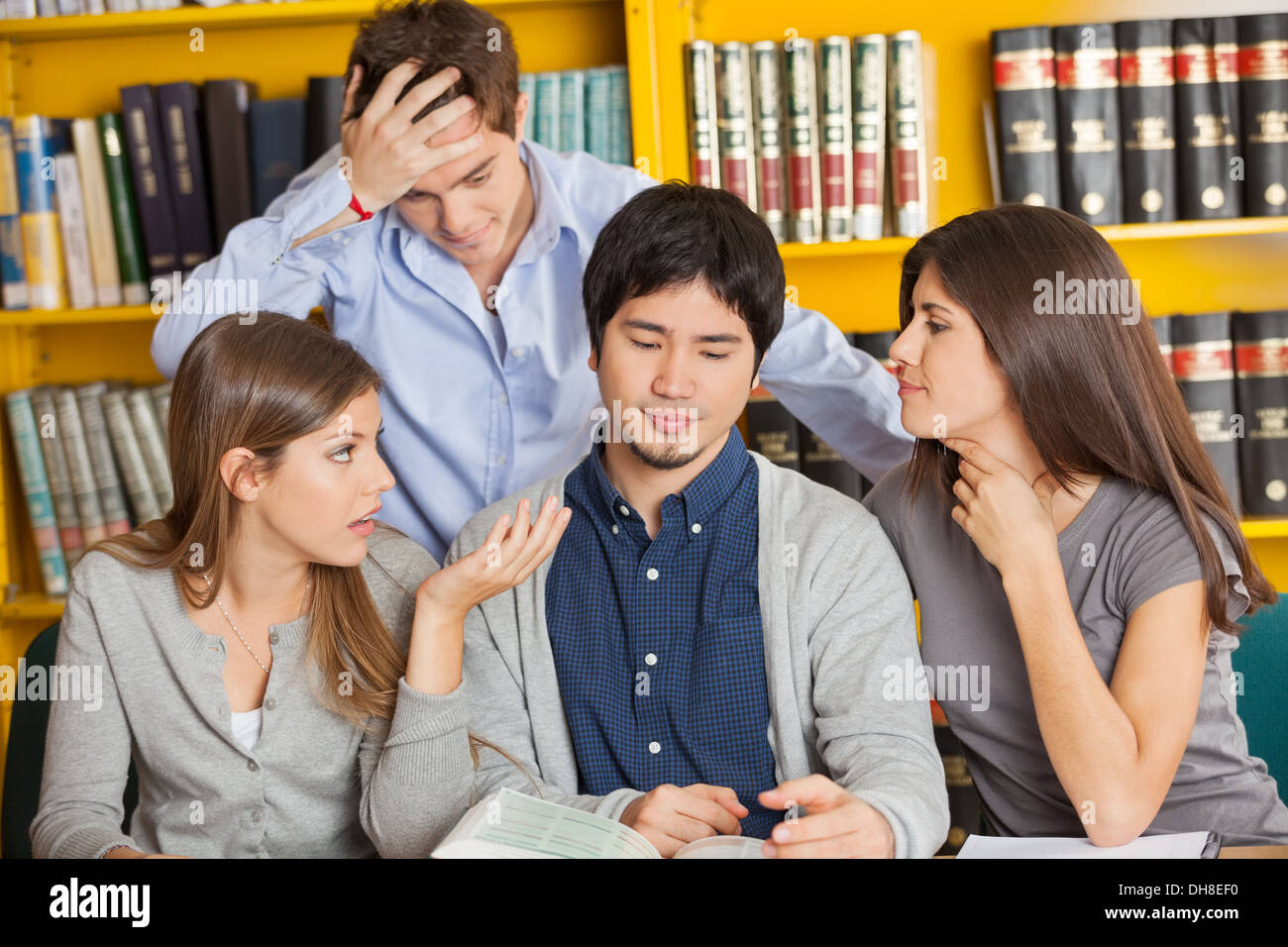 Worried Students With Book Sitting In Library Stock Photo - Alamy