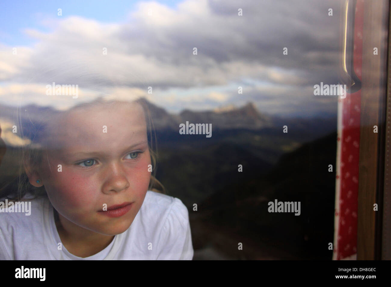 Dreamy girl staring through window with reflection of mountains and ...