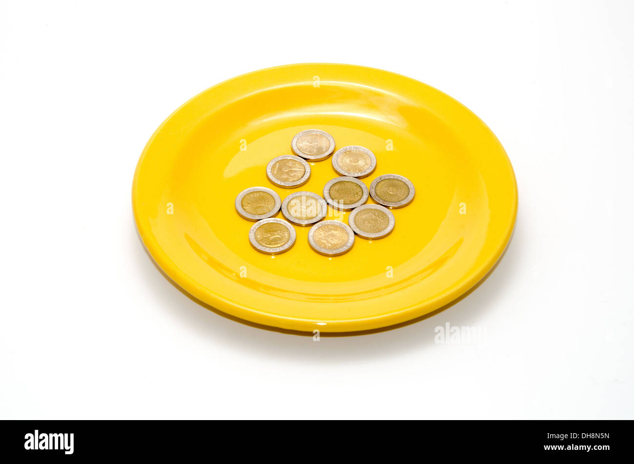 Yellow plate with coins Stock Photo - Alamy