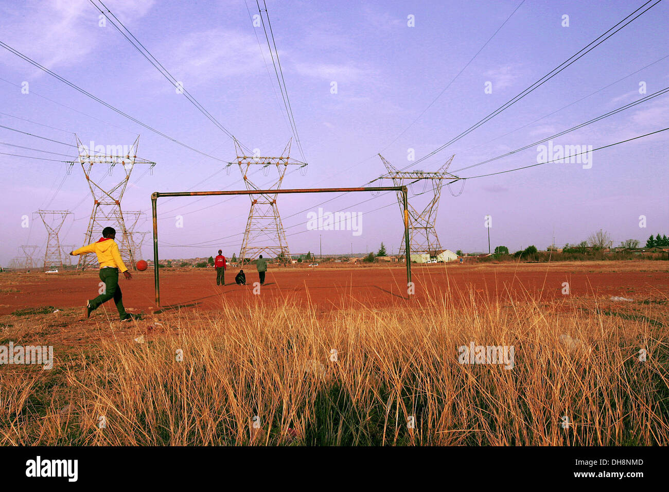 A young boy plays soccer under electrical pylons at Orange Farm ...
