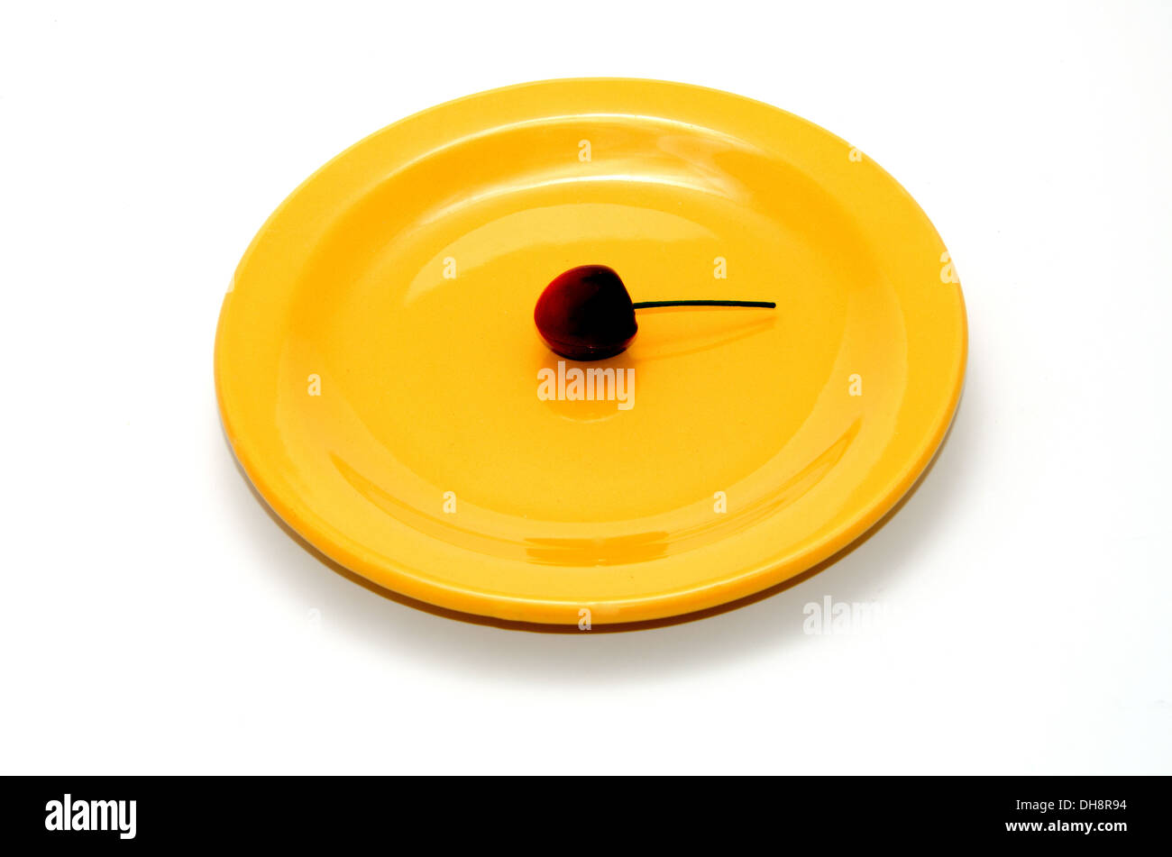 Yellow plate with plastic cherry Stock Photo - Alamy
