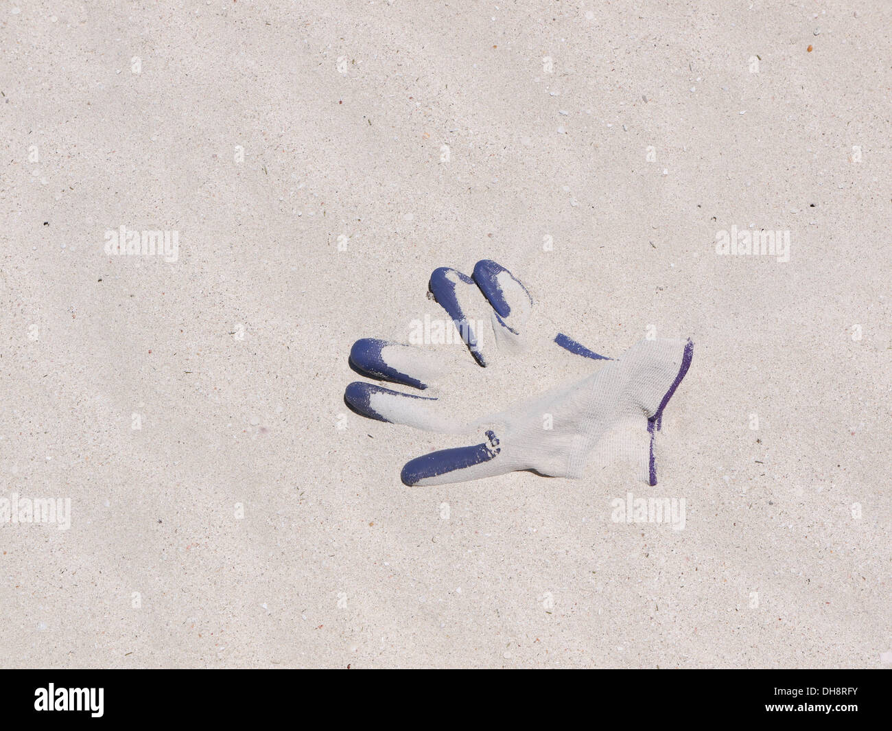 Lost glove partially covered in sand on a beach Stock Photo - Alamy