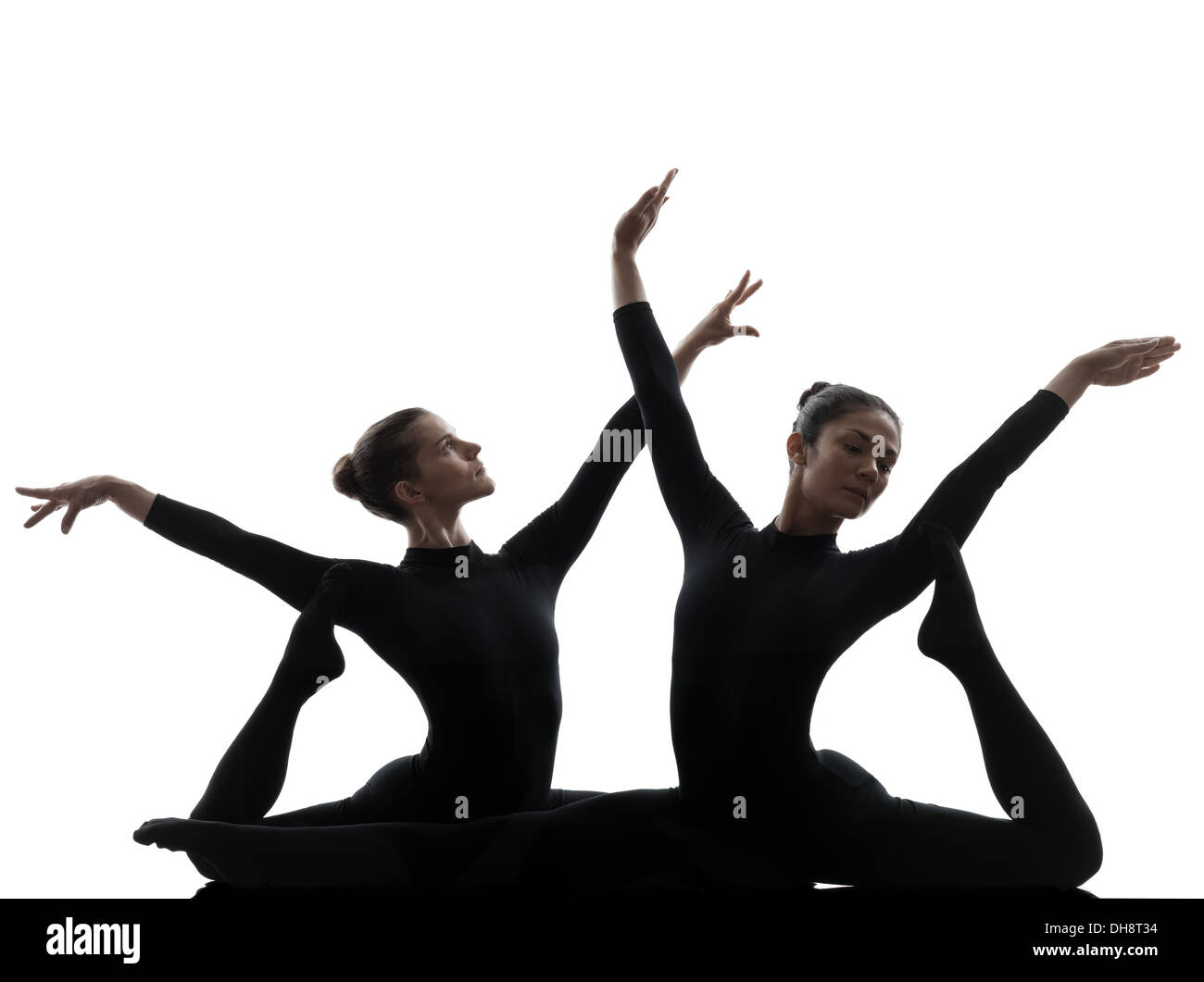 two women contortionist practicing gymnastic yoga in silhouette on ...
