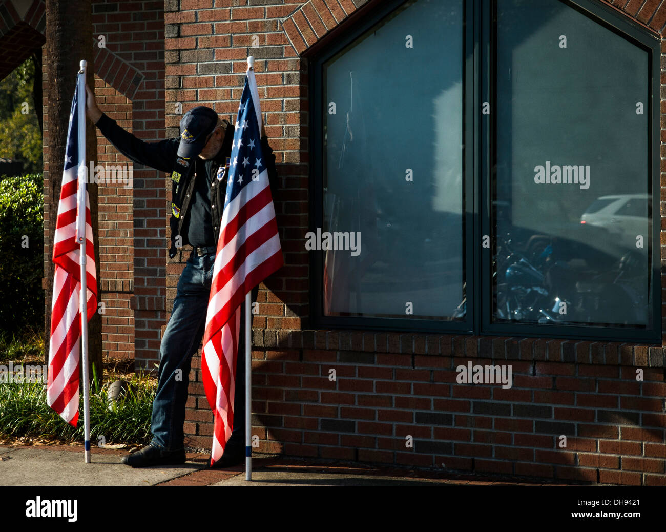 A South Carolina Patriot Guard member holds American flags outside the ...