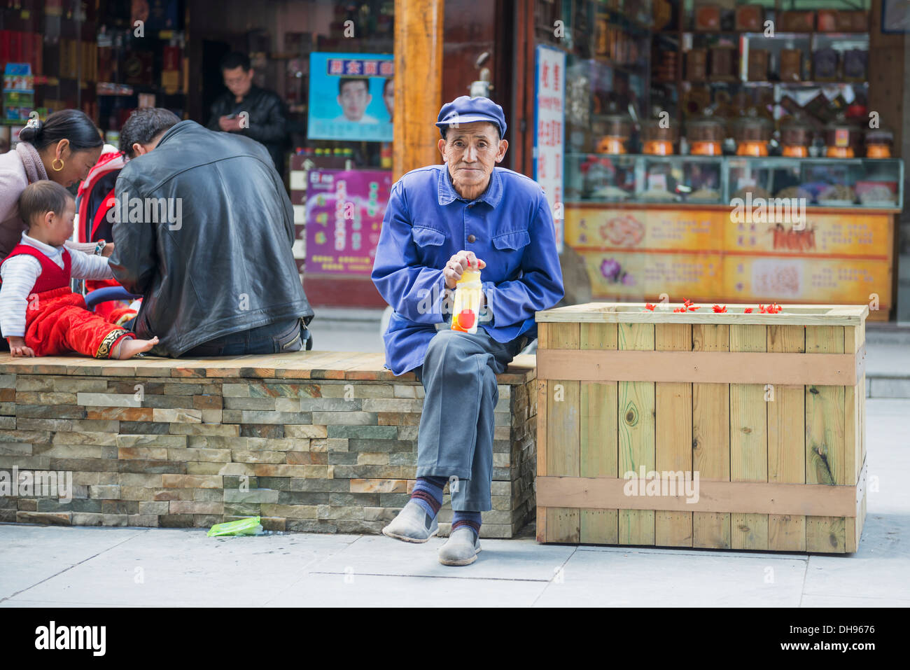 A Senior Man Sitting On A Street Bench; Songpan, Sichuan, China Stock ...