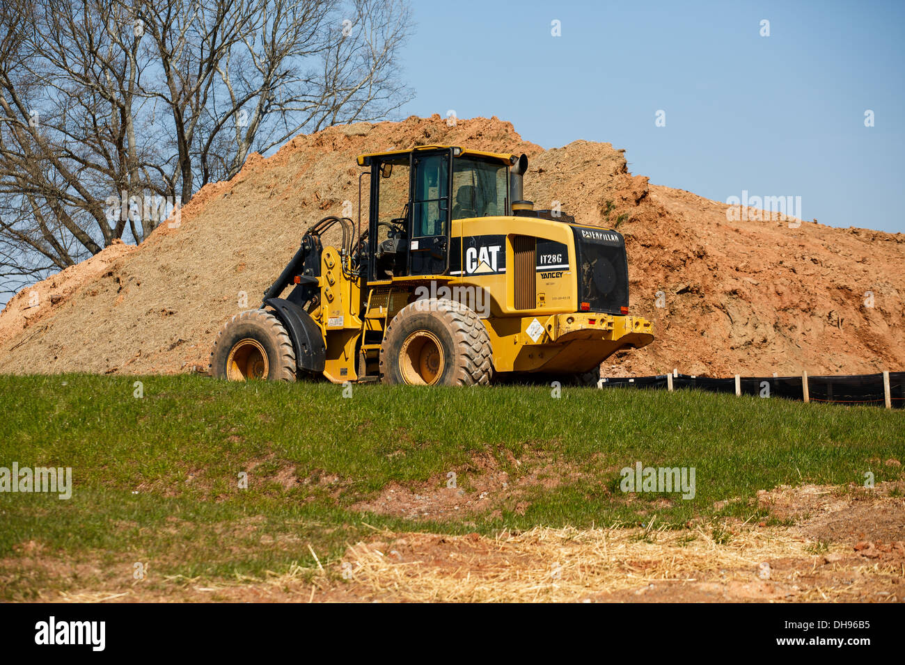 A large, yellow, industrial earth mover by a pile of dirt on a ...