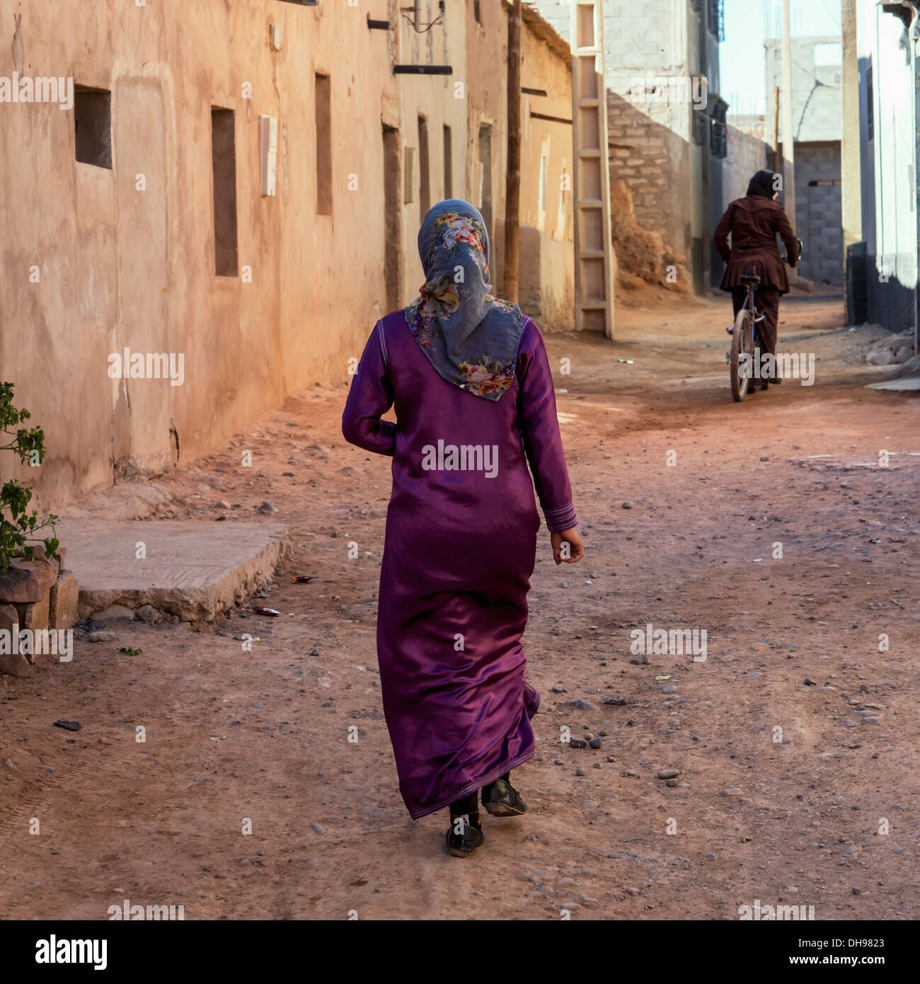 A Pedestrian And Cyclist Going Down An Alley Between Buildings; Morocco ...