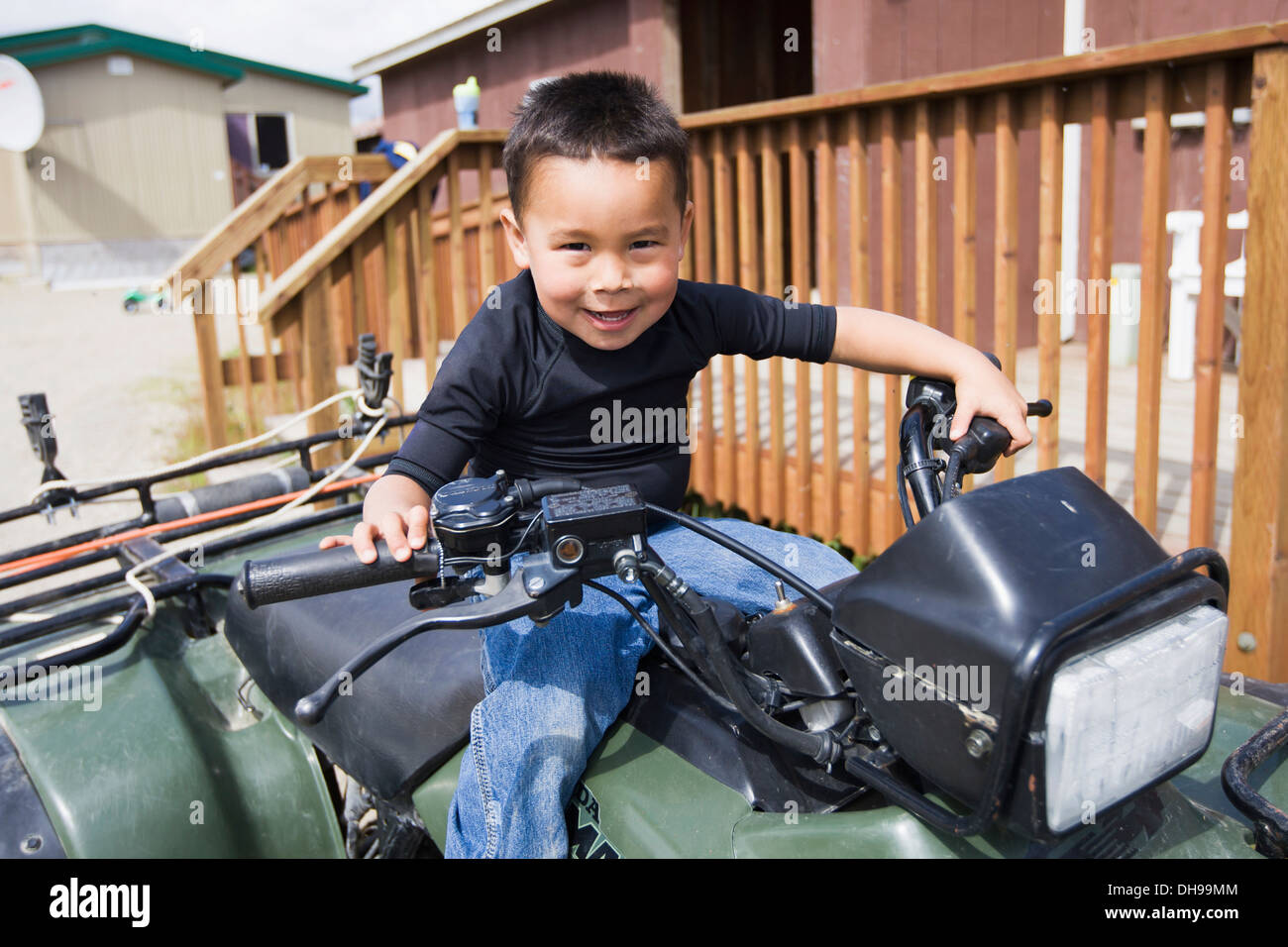 A Young Boy Smiles Playfully While Sitting Atop A Four Wheeler And ...