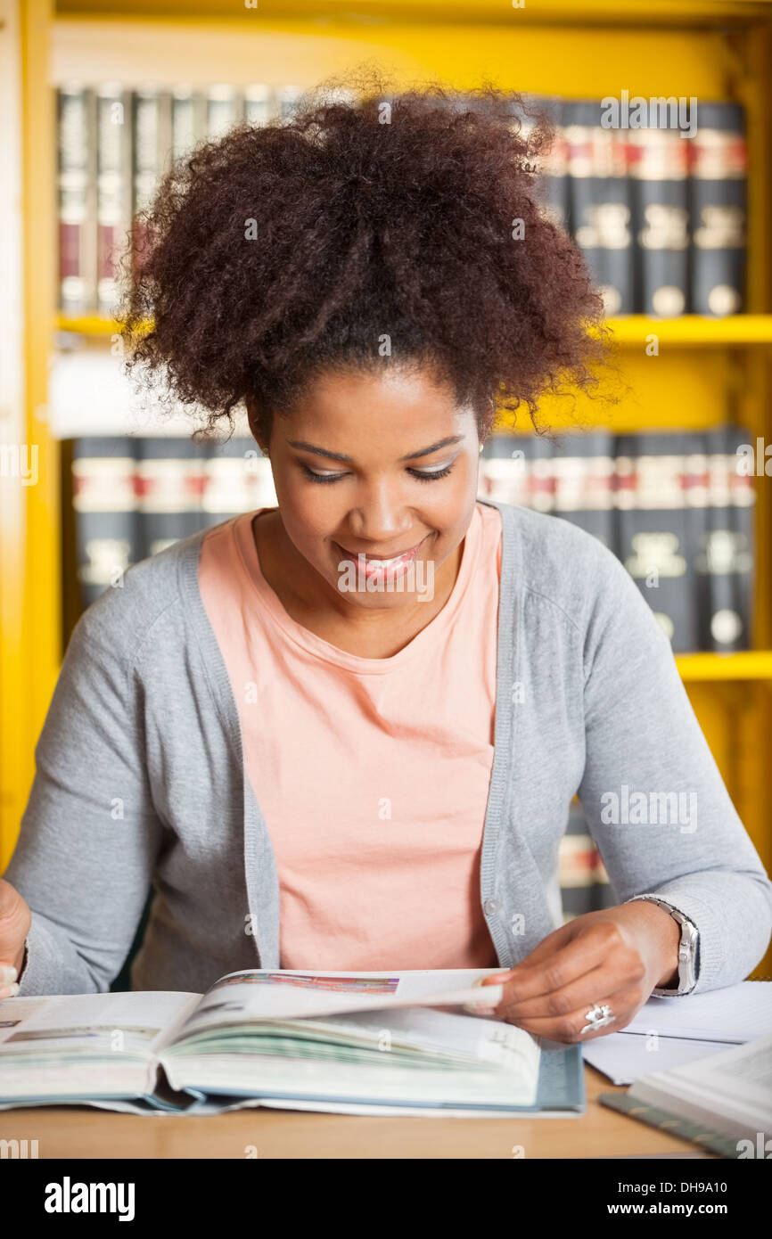 Woman Smiling While Reading Book In College Library Stock Photo - Alamy