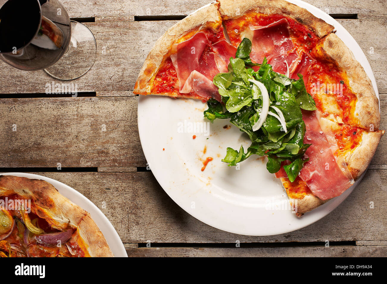 looking down on a half eaten pizza on a wooden table Stock Photo - Alamy