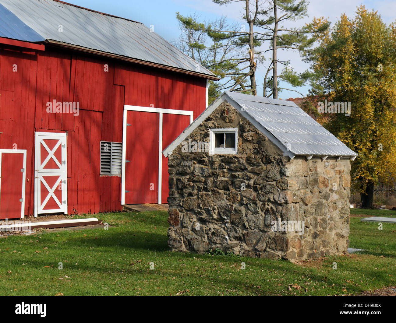 A vintage stone spring house in front of a red barn Stock Photo - Alamy