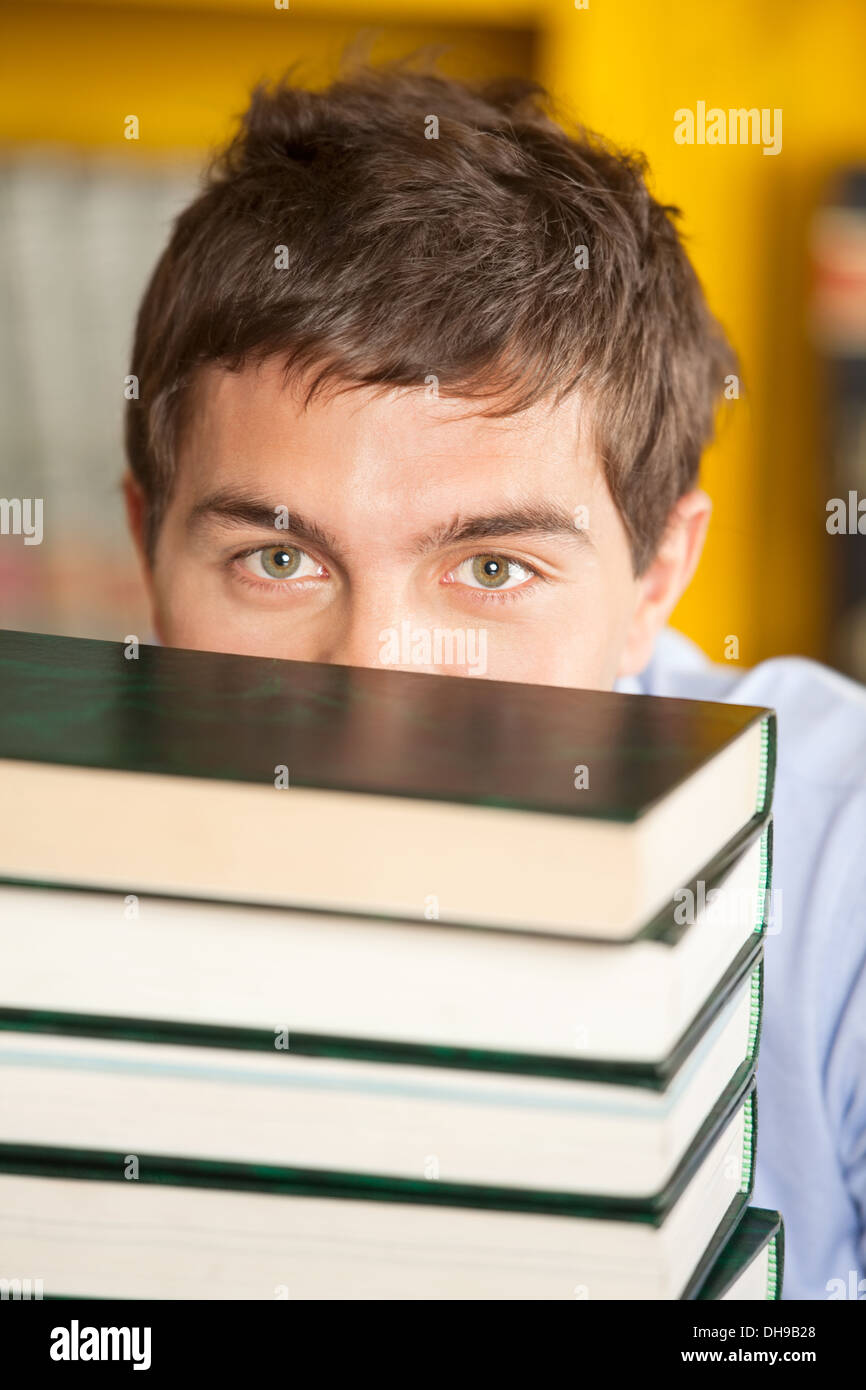 Student Peeking Over Piled Books In University Library Stock Photo - Alamy