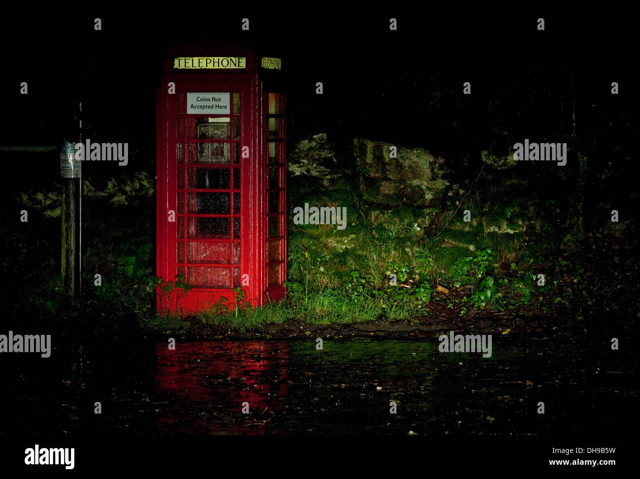 Red Telephone box seen in car headlights at night in the rain at ...