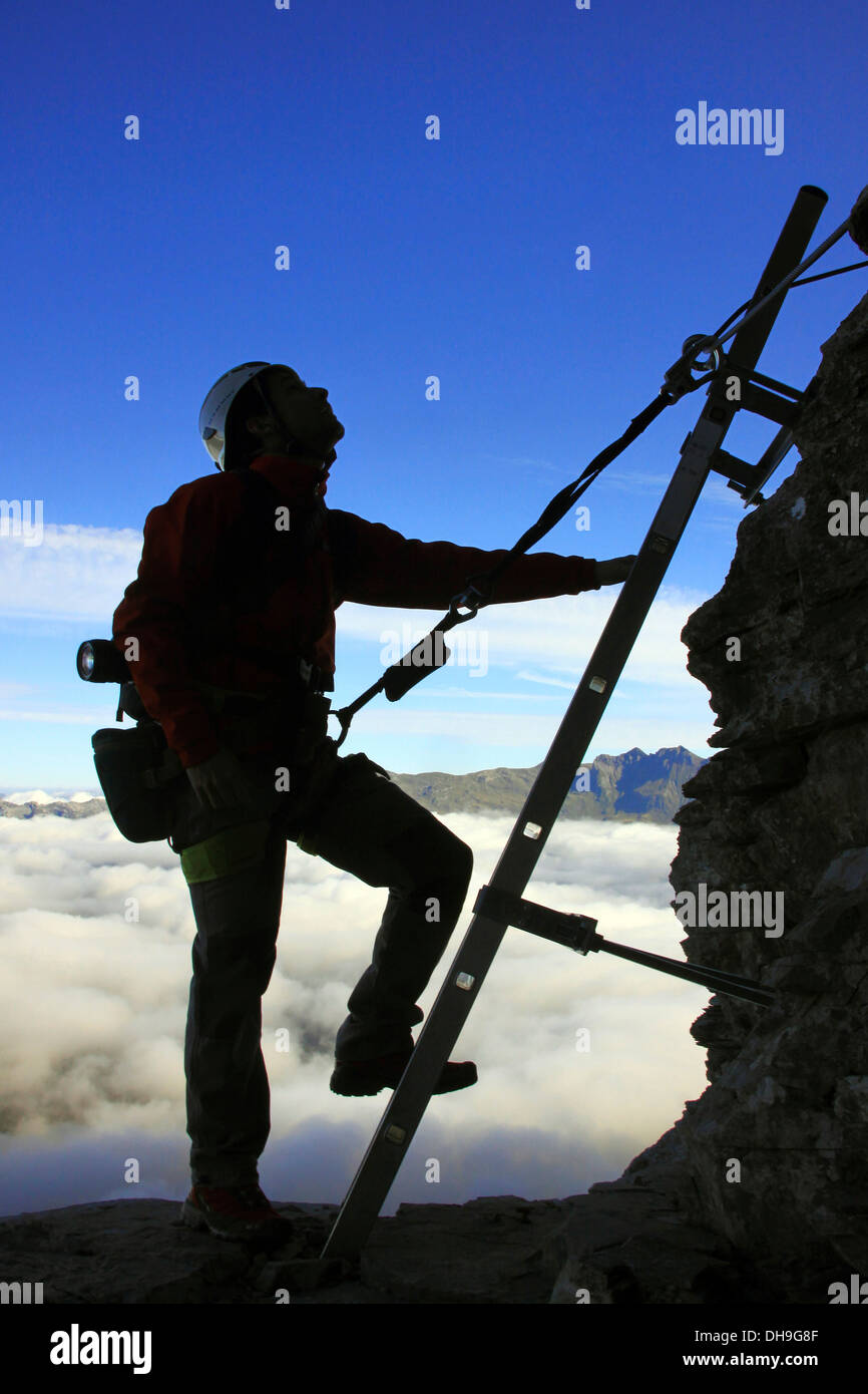 Silhouette of mountain climber climbing metal ladder of Via ferrata in ...