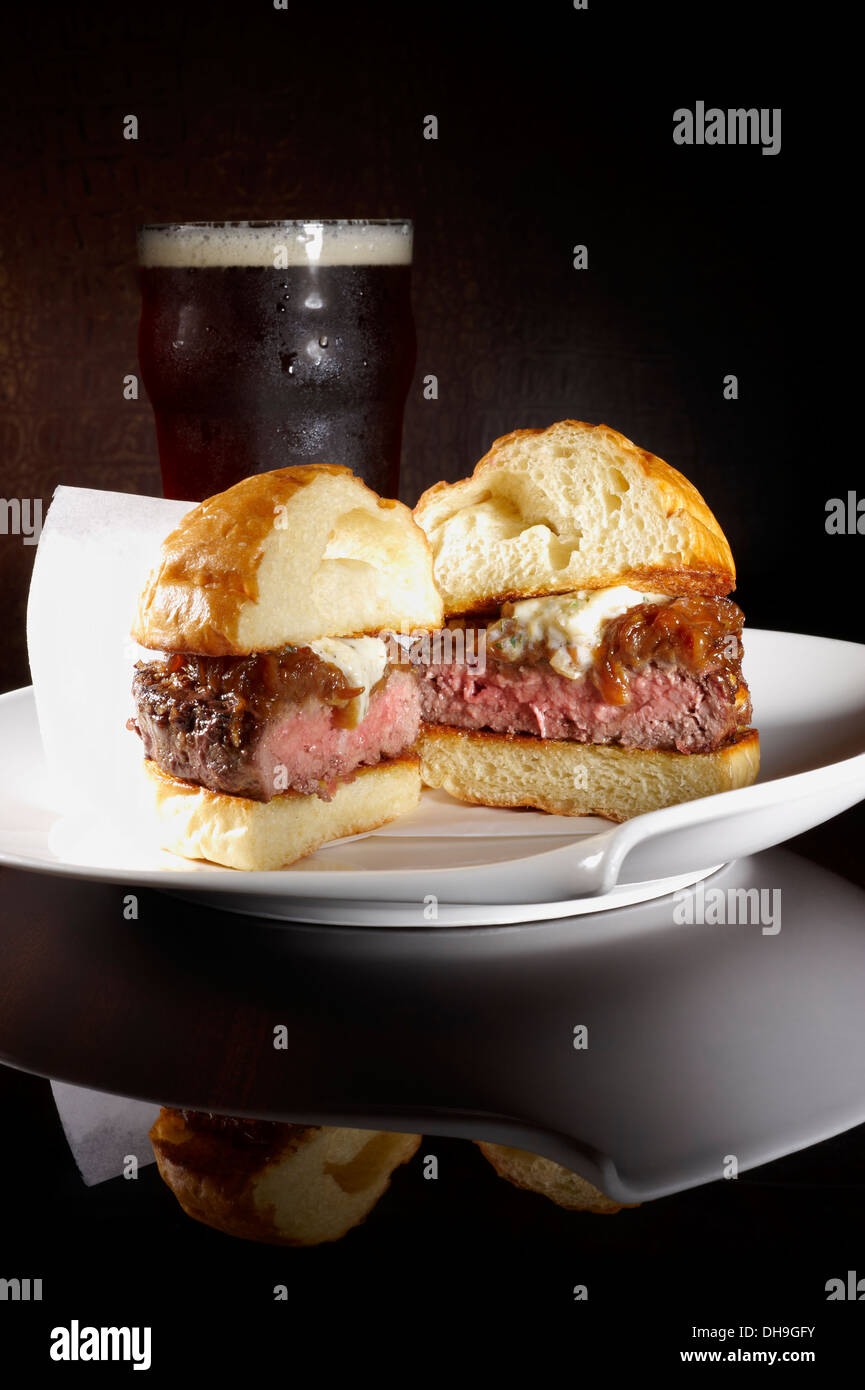 Burger cut in half with beer in background Stock Photo - Alamy