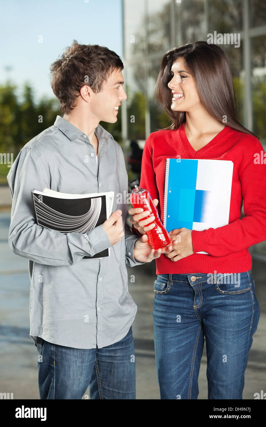 Student Giving Juice Bottle To Friend On Campus Stock Photo - Alamy