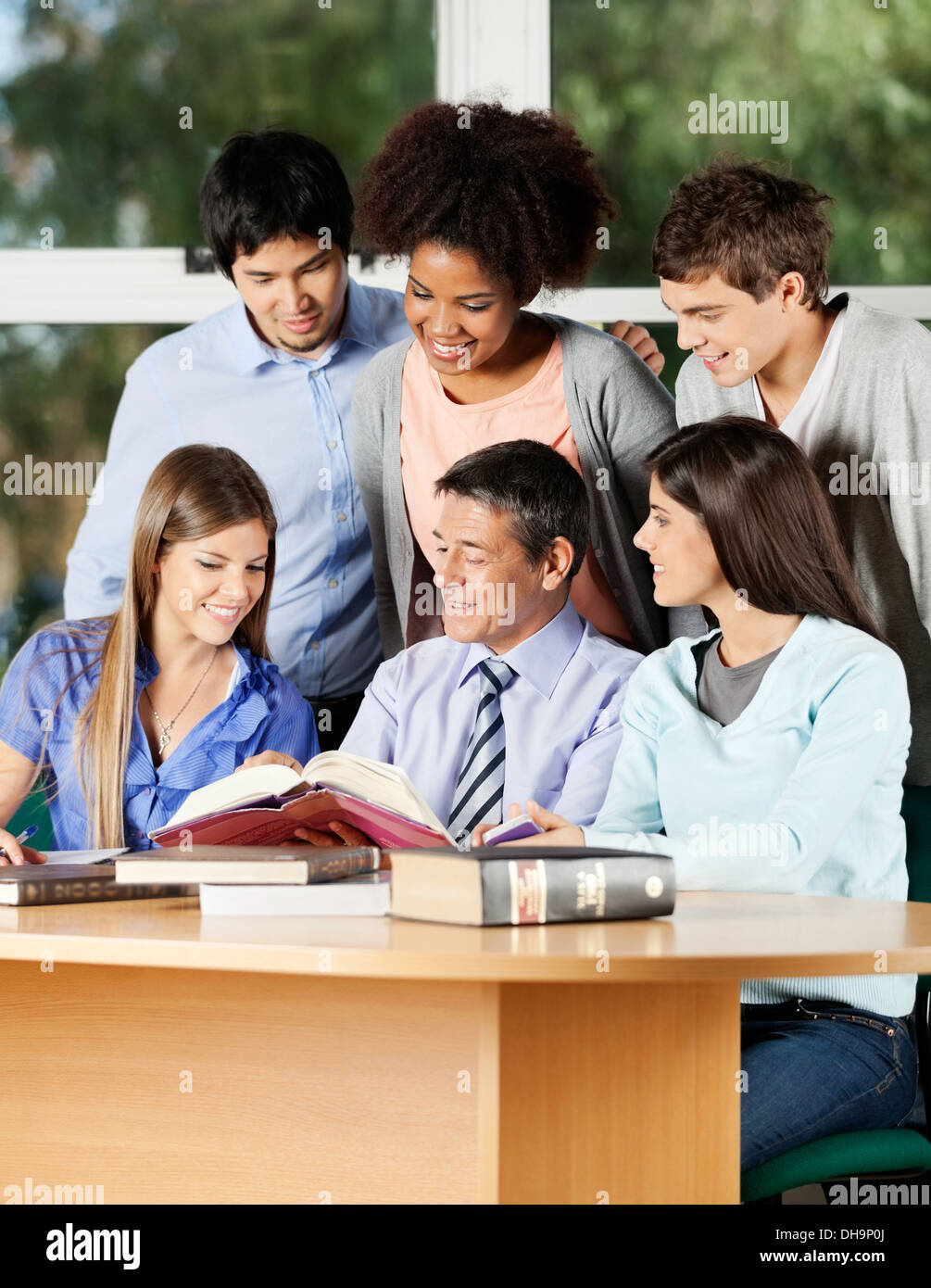 Professor Explaining Students At Desk In Classroom Stock Photo - Alamy