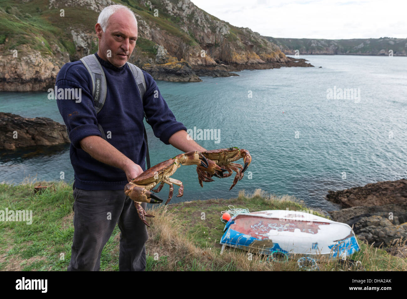 A local fisherman wearing a traditional Guernsey jumper holding two ...