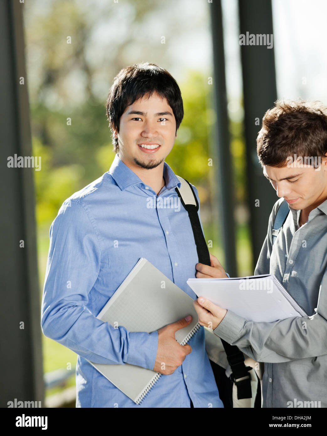 Male Student With Friend Reading Book In Campus Stock Photo - Alamy