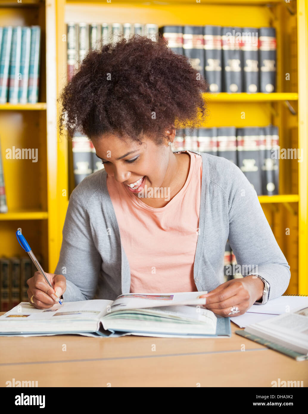 Student Writing In Book At University Library Stock Photo - Alamy