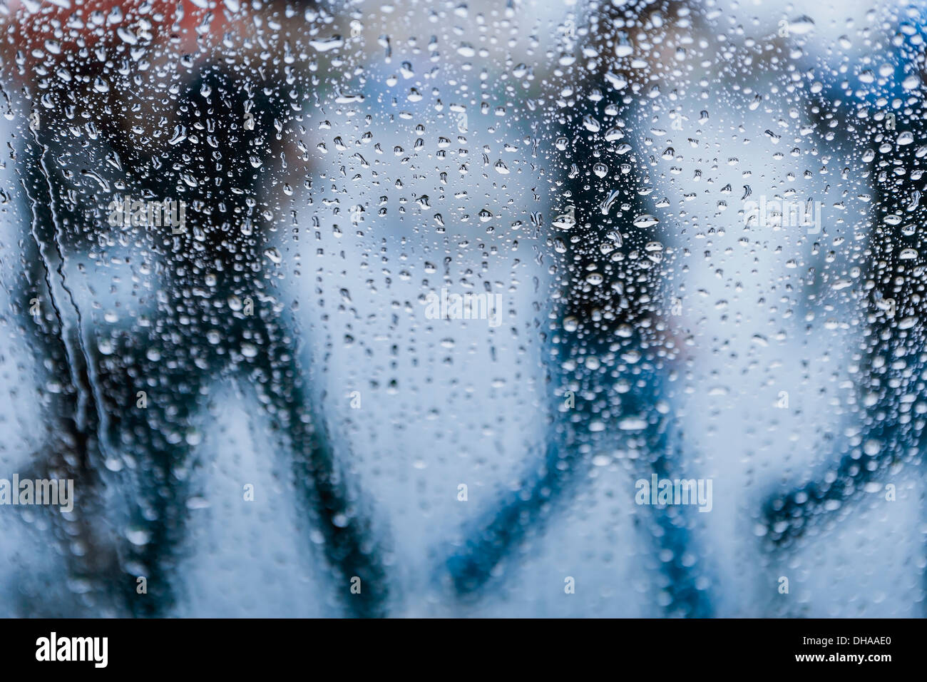 A Window Covered With Rain Drops And Silhouettes Of People Walking By ...