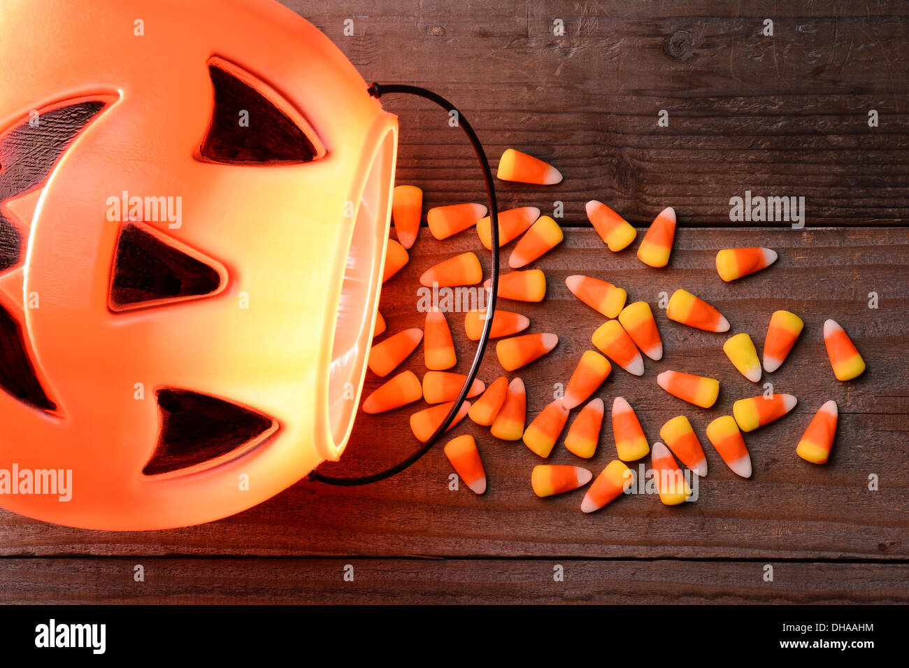 Plastic pumpkin and candy corn spill on a rustic wood background ...