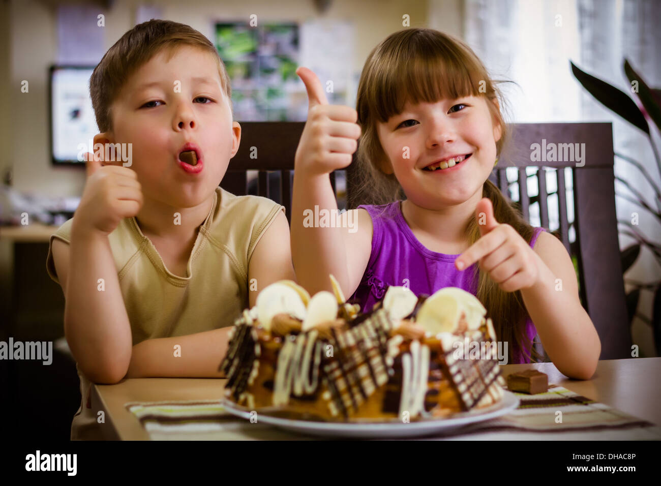 Children sit near a table and eat a cake Stock Photo - Alamy