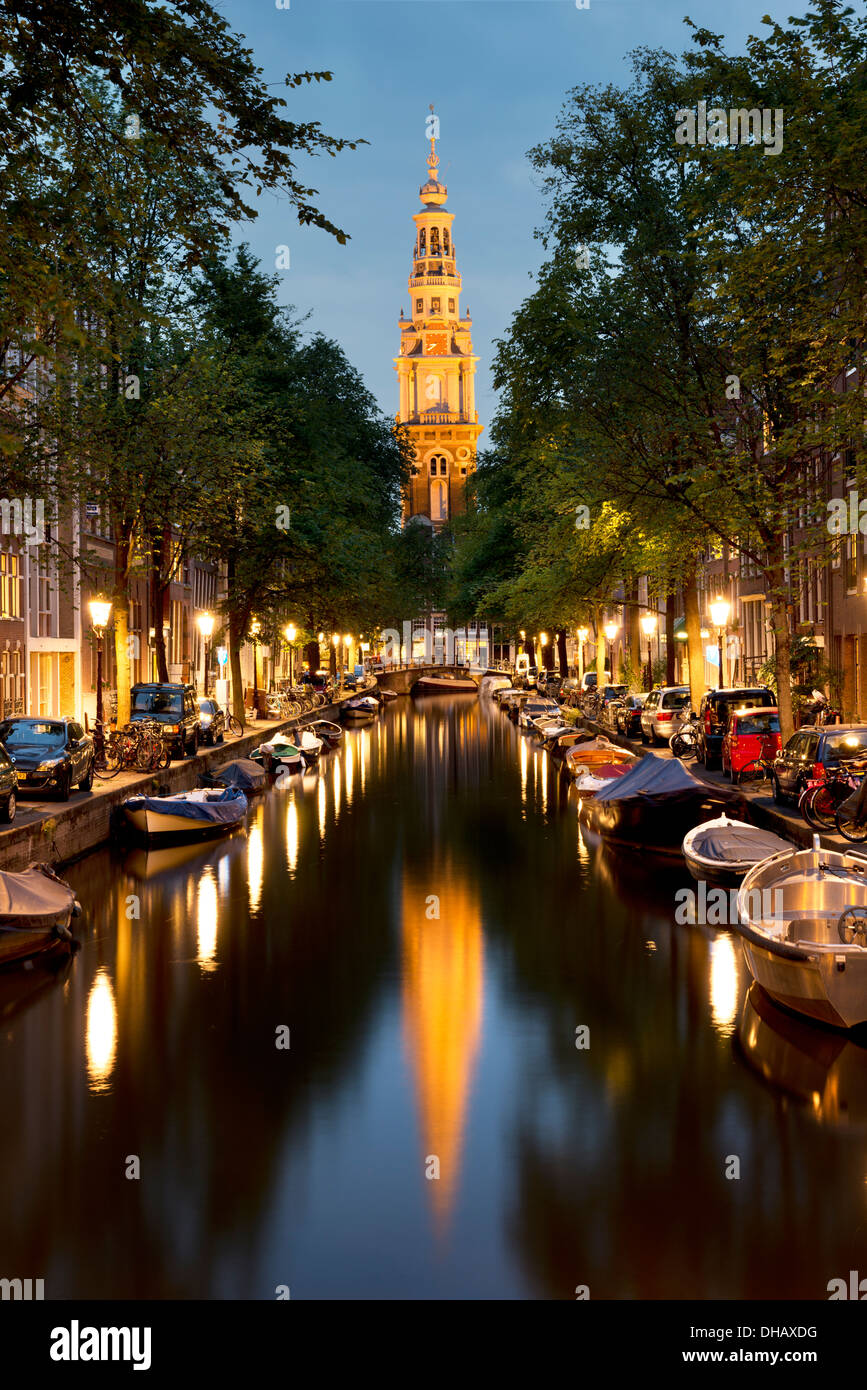 The Zuiderkerk illuminated at night and reflected in a canal lined with ...