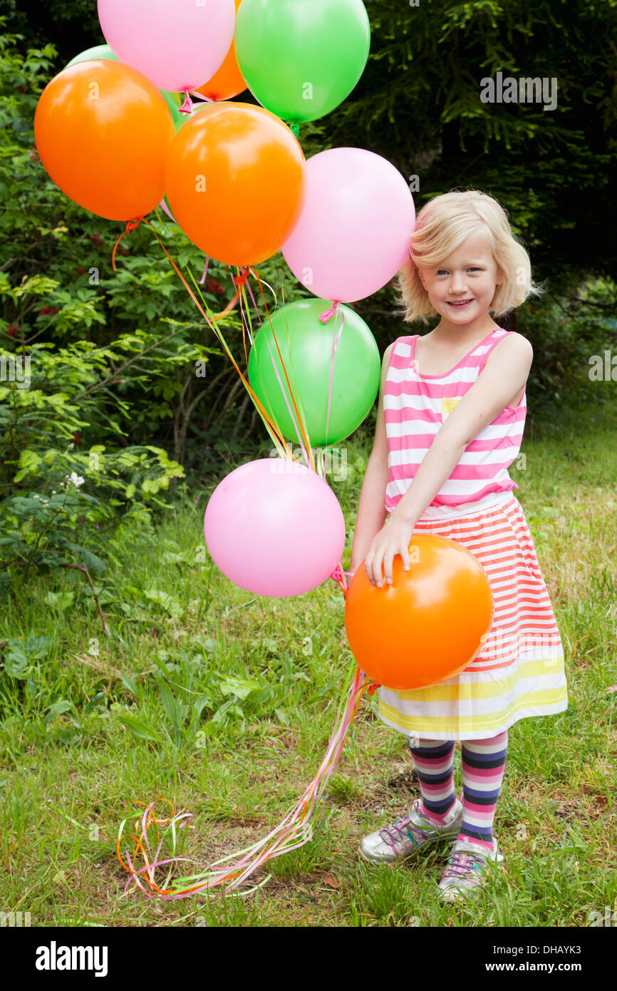 A Young Girl Standing On The Grass With A Colourful Bouquet Of Balloons ...