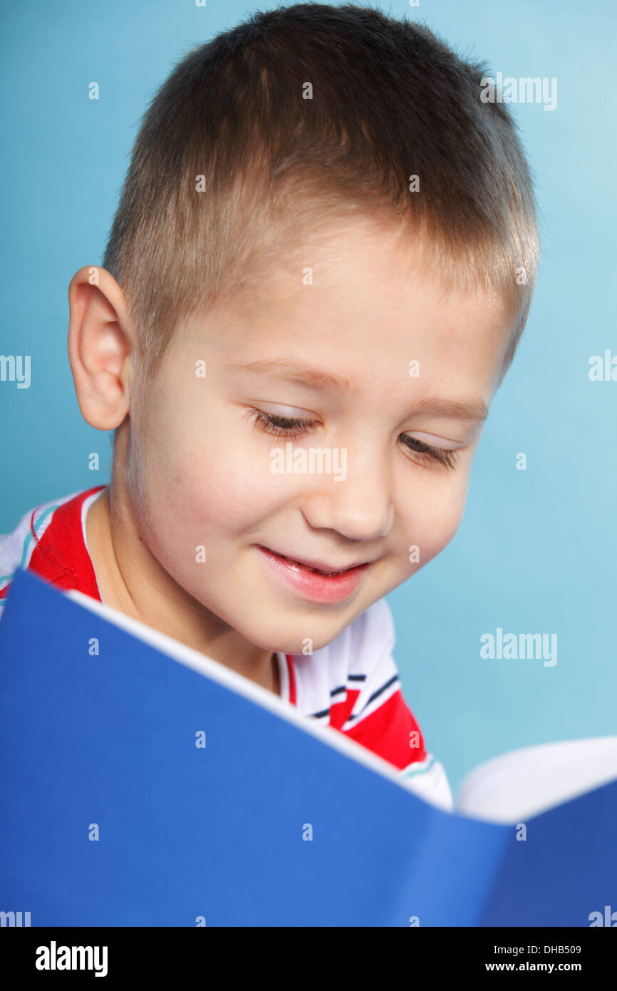 Young boy reading a book, child kid on blue background holding an open ...