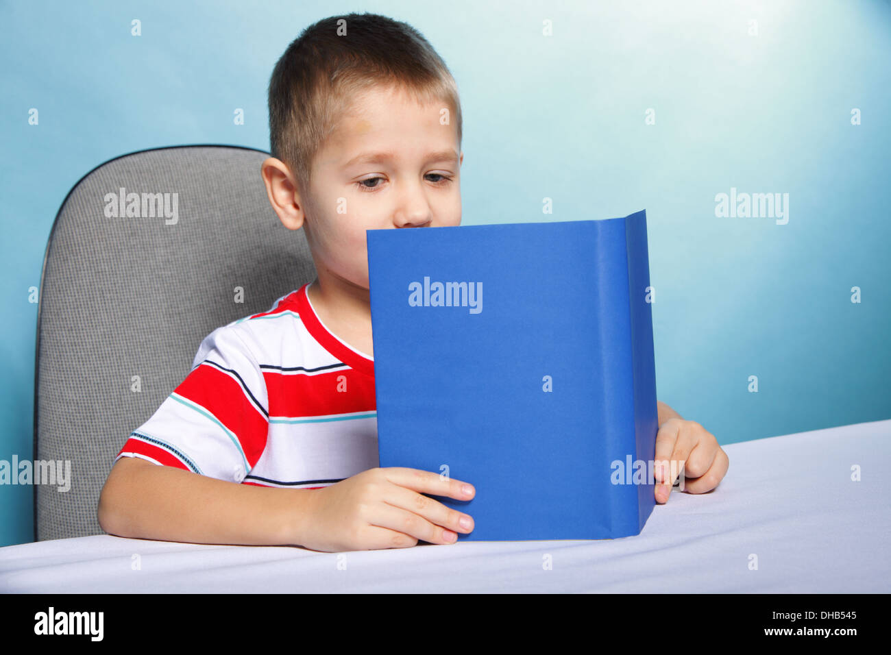 Young boy reading a book, child kid on blue background holding an open ...