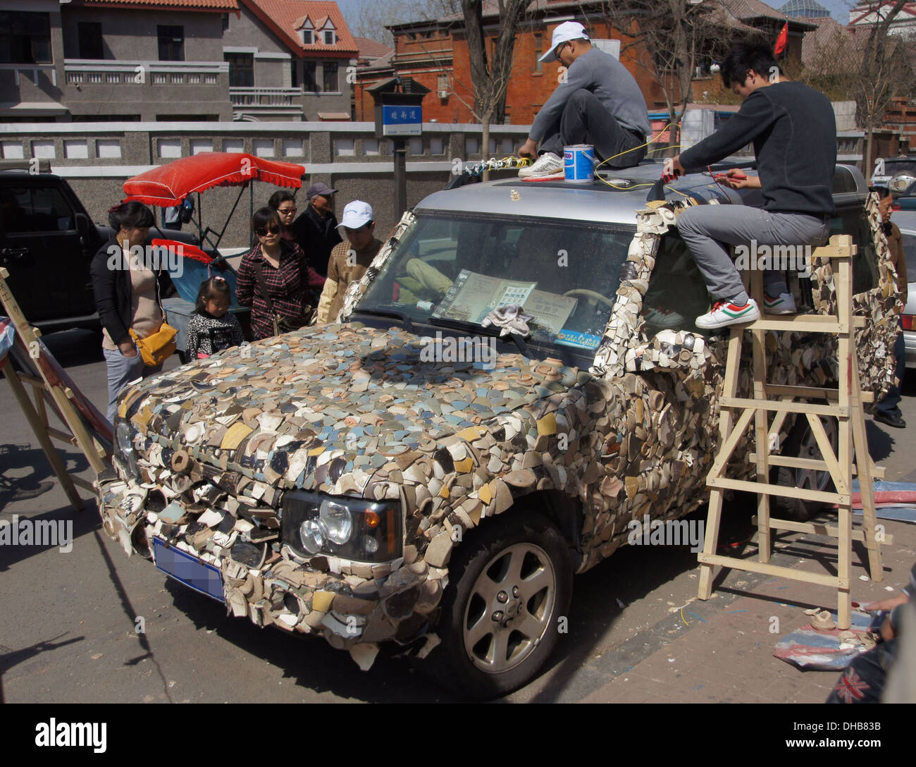 Landrover decorated with pottery and porcelain Workers decorate a Land ...