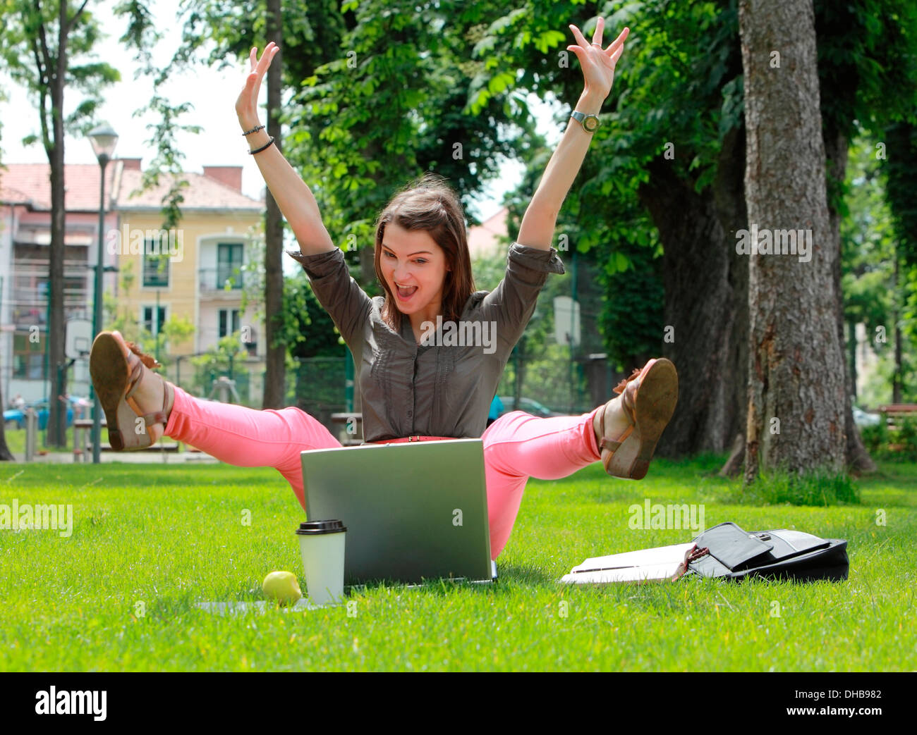 Excited happy woman with a laptop raising her hands and legs up in an ...