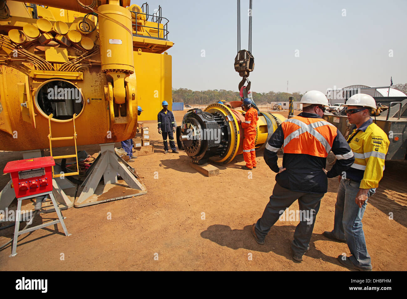 Mining in Africa. Men in hard hats assembling heavy mine machinery ...