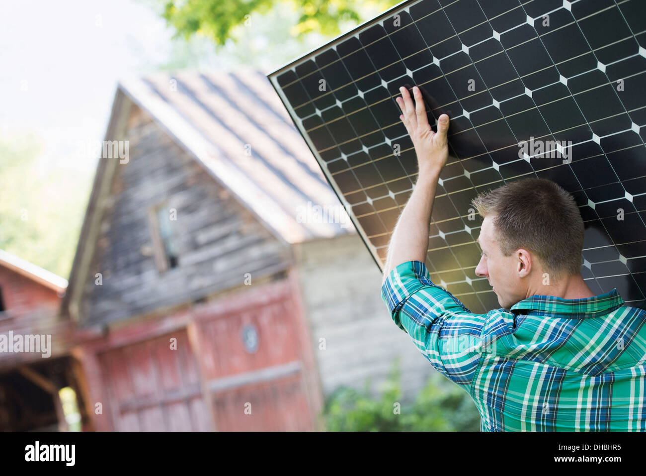 A man carrying a solar panel towards a building under construction ...