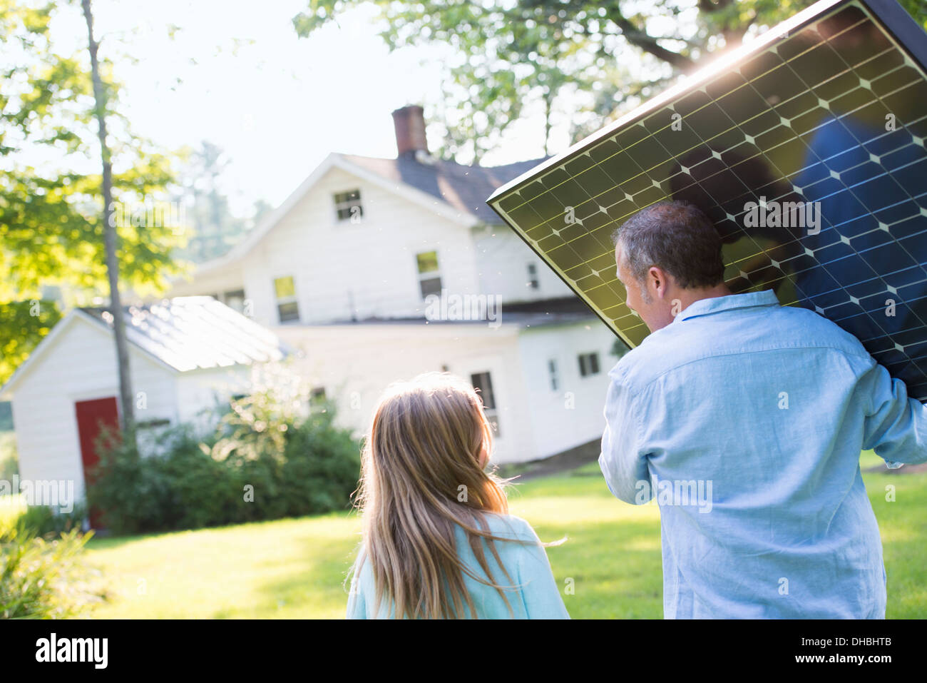 A man carrying a solar panel towards a building under construction ...