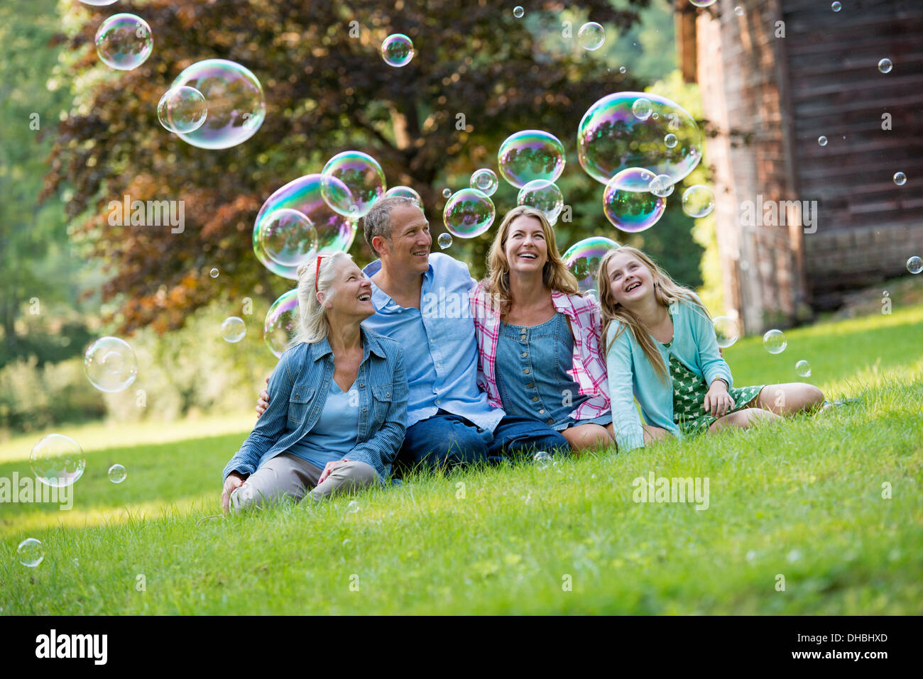 A family sitting on the grass outside a bar, blowing bubbles and ...