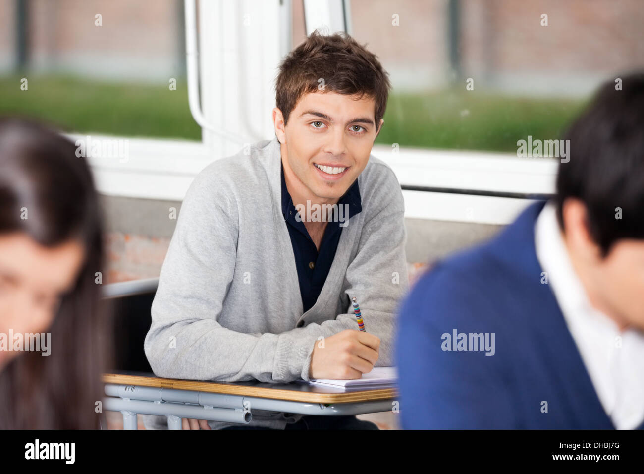 University Student Sitting At Desk With Classmates In Classroom Stock ...