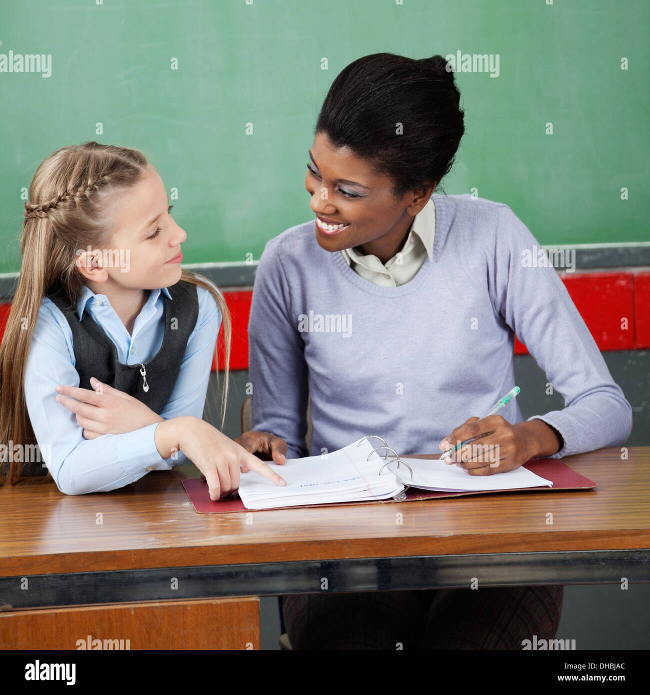 Professor Looking At Schoolgirl At Desk Stock Photo - Alamy