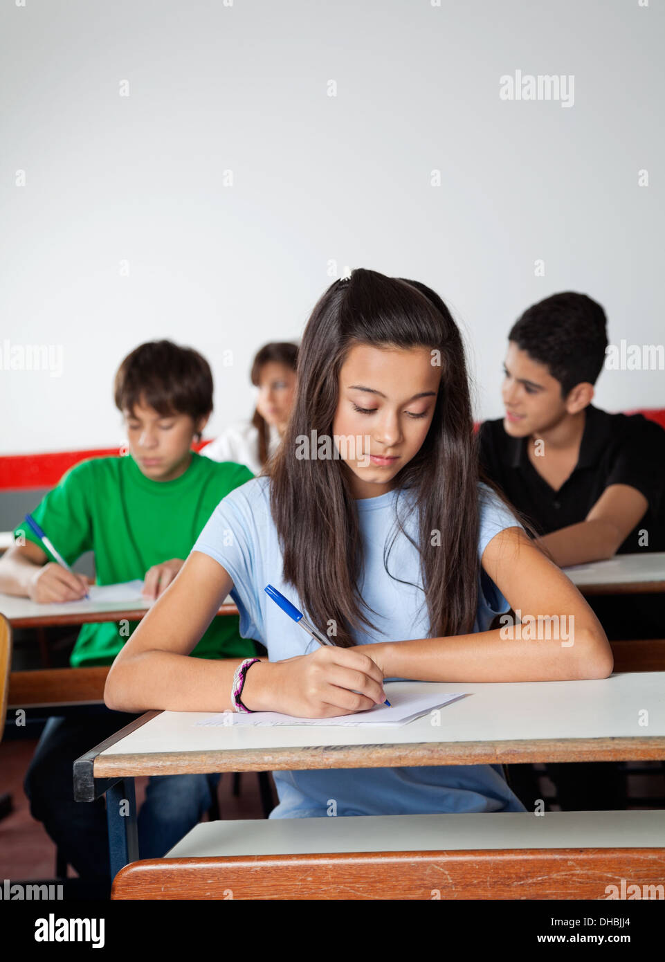 Female Student Writing Paper At Desk In Examination Stock Photo - Alamy
