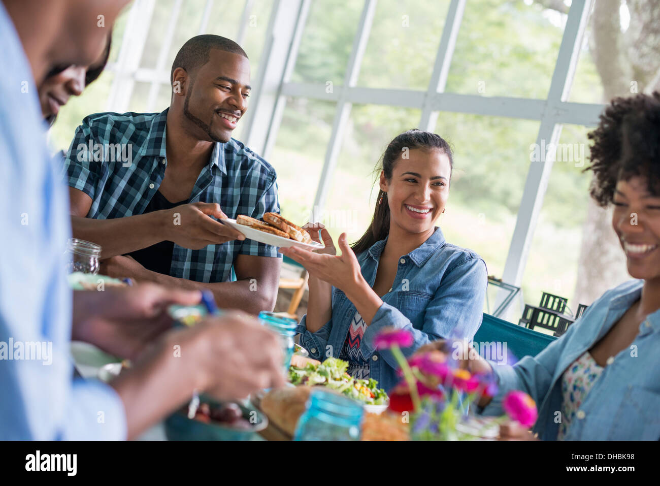 A group of women and men around a table sharing a meal in a farmhouse ...