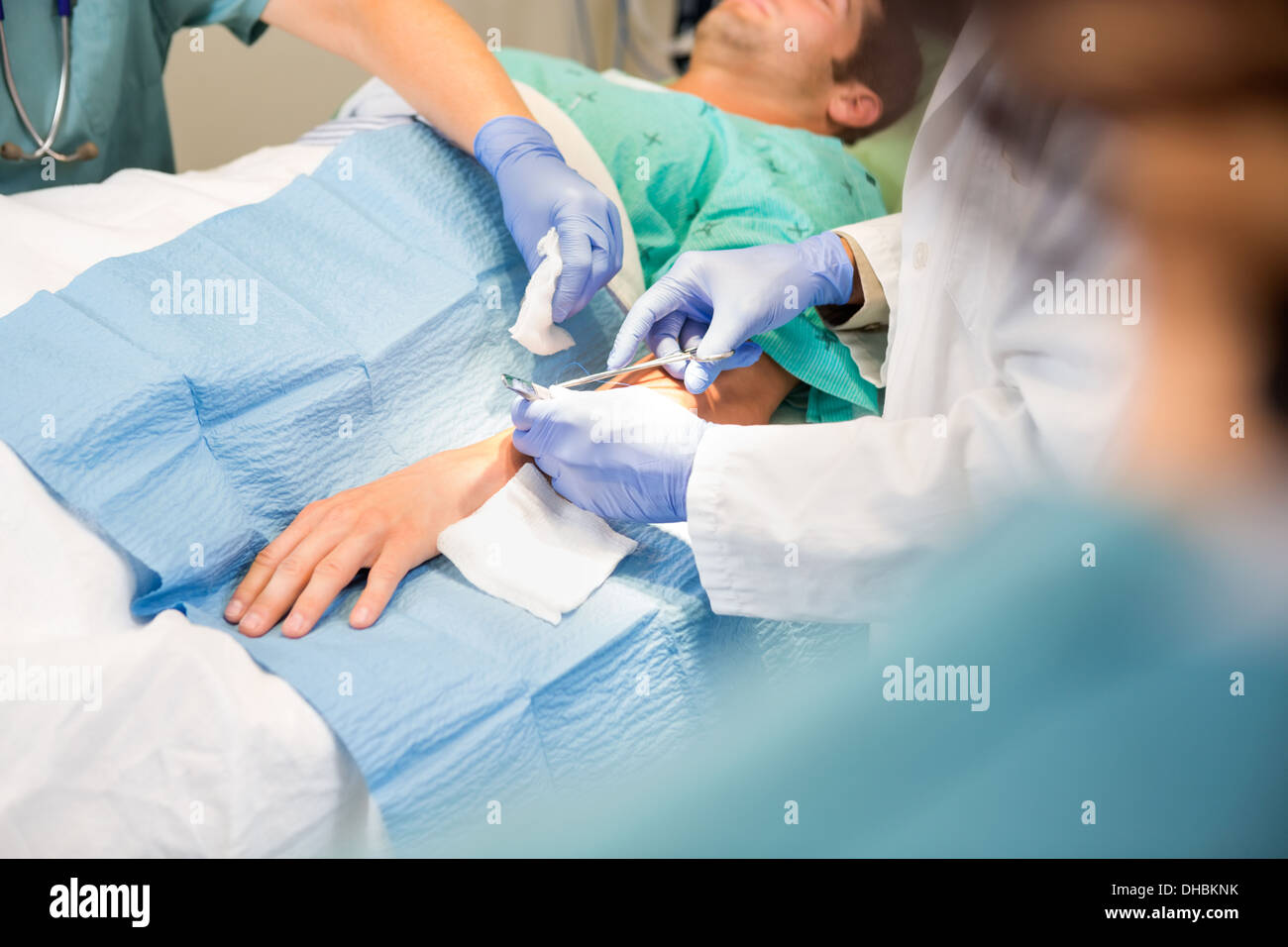 Doctor Stitching Patient's Wound While Nurse Assisting Him Stock Photo ...