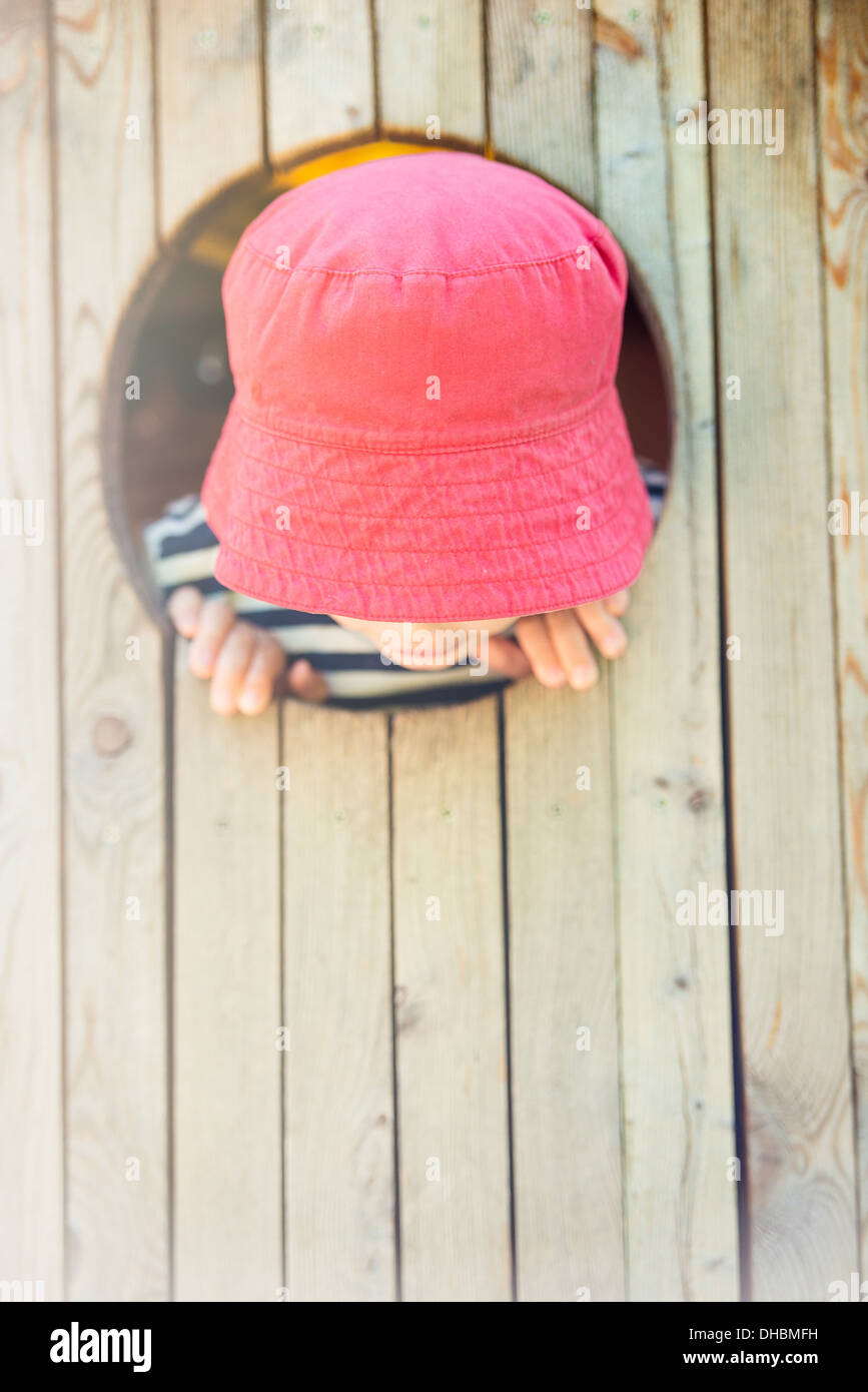 Childhood lifestyle moment. Little girl in read hat looking down from ...