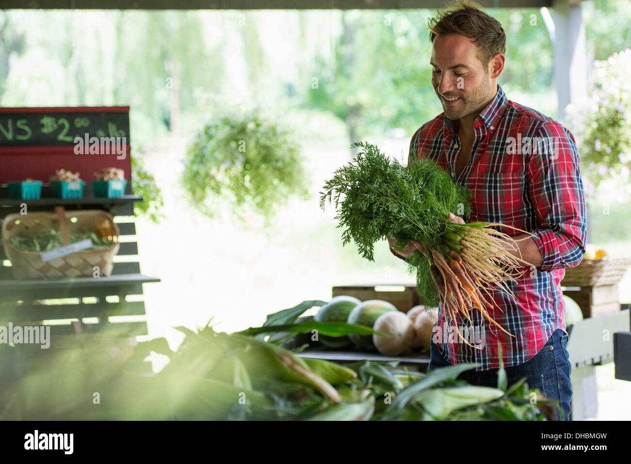 A farm stand with fresh organic vegetables and fruit. A man holding ...