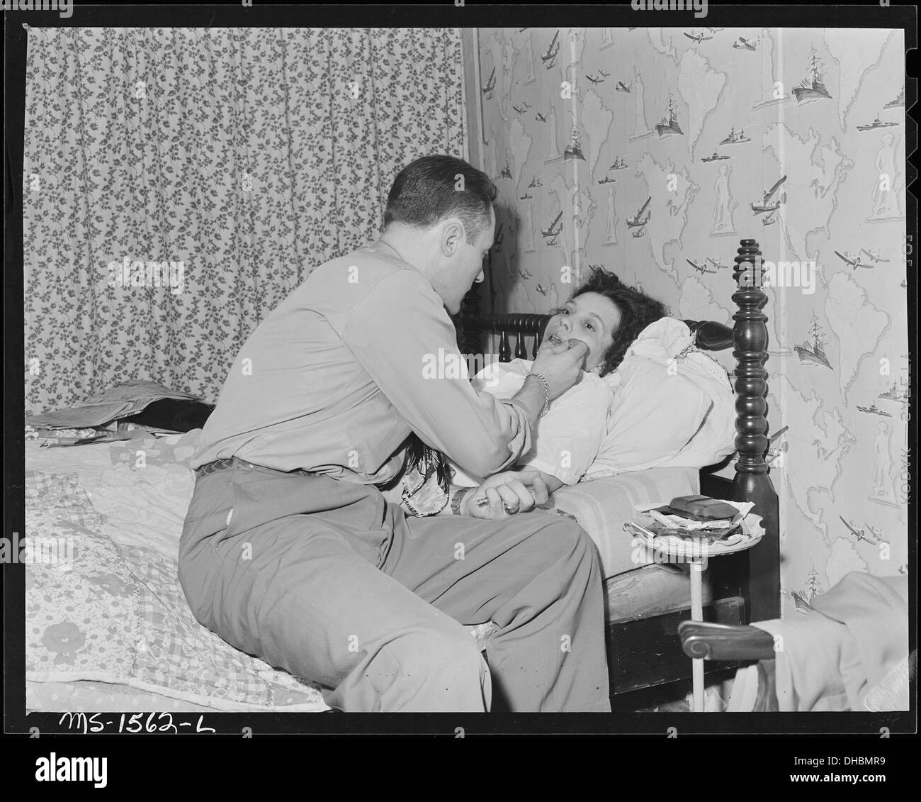 This photograph features Dr. R.V. Tokar during a house call, a common practice at the time. The ...