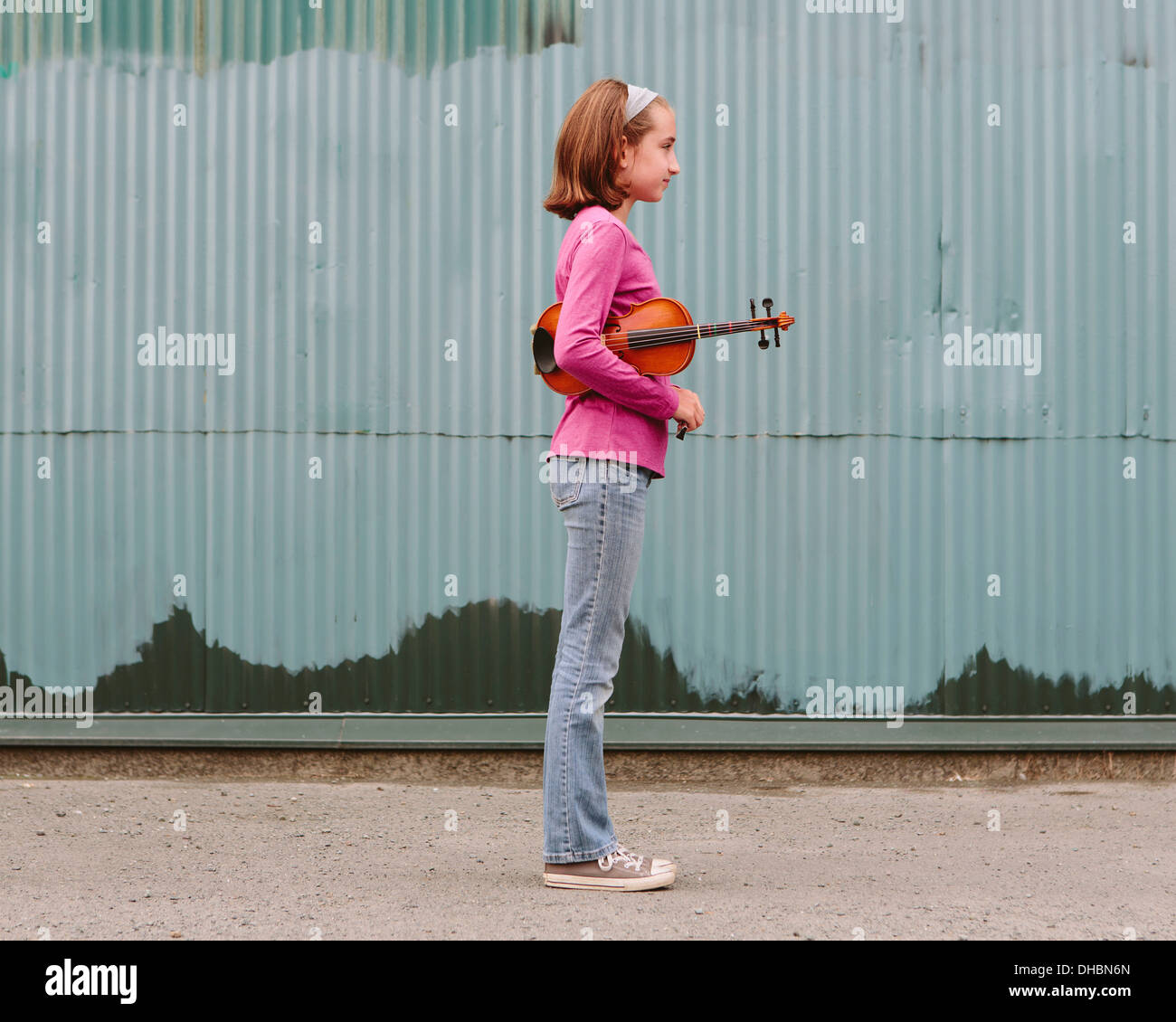 A ten year old girl holding a violin under her arm, standing on a ...