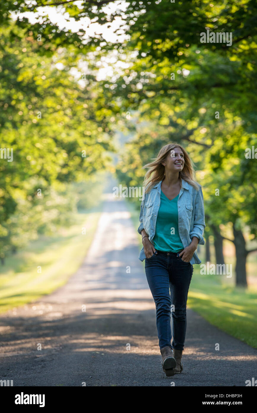 A woman walking down a tree lined path Stock Photo - Alamy