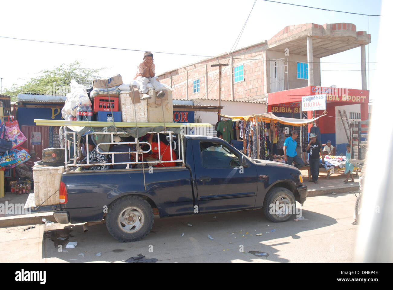 A crowded truck with people and luggage and a child perched on the top ...